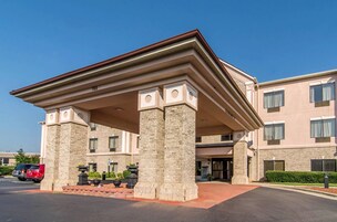 Entrada de hotel com varanda coberta, colunas de pedra e telhado vermelho.
