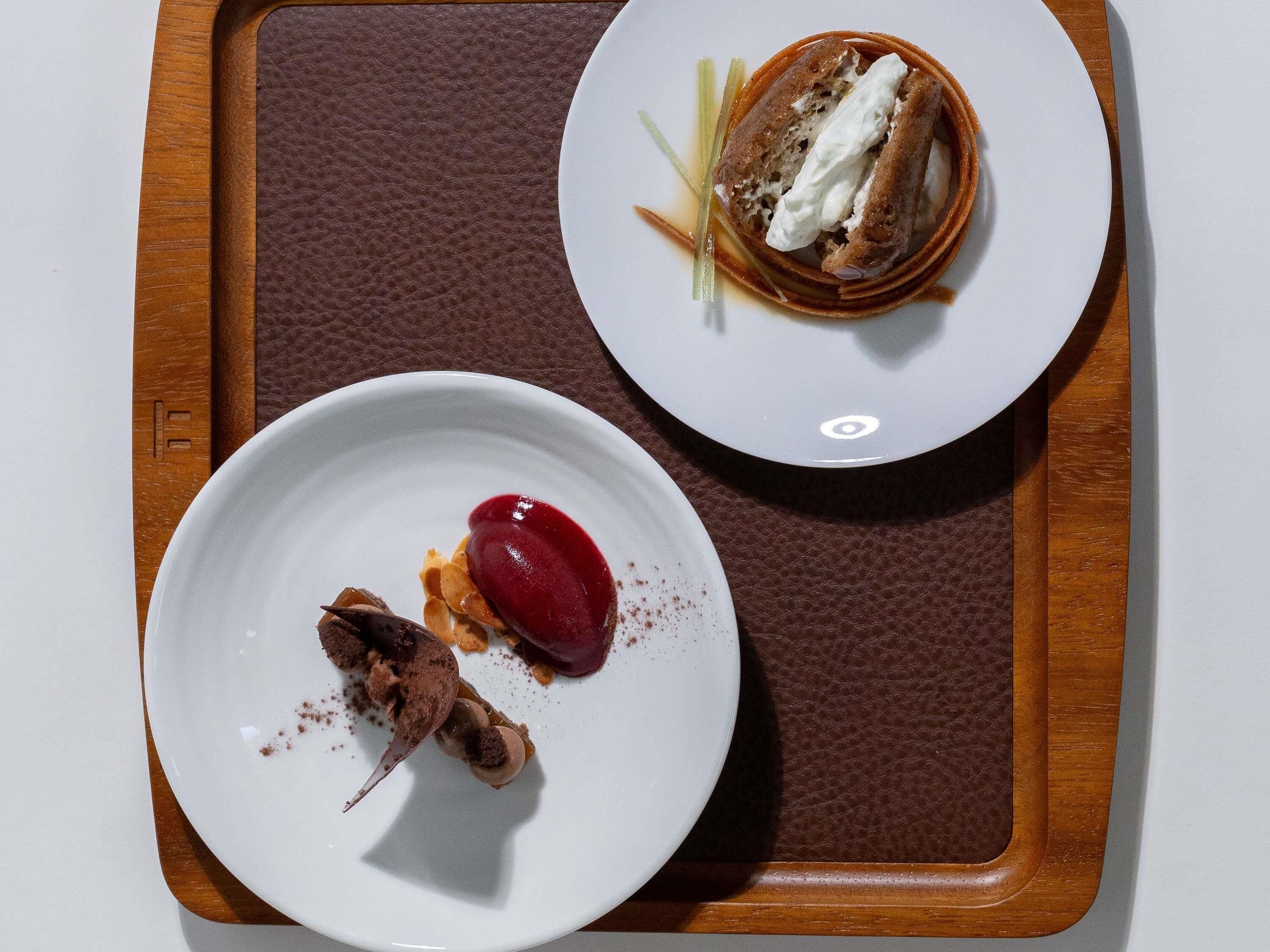 Duas travessas de comida sobre uma bandeja de madeira.