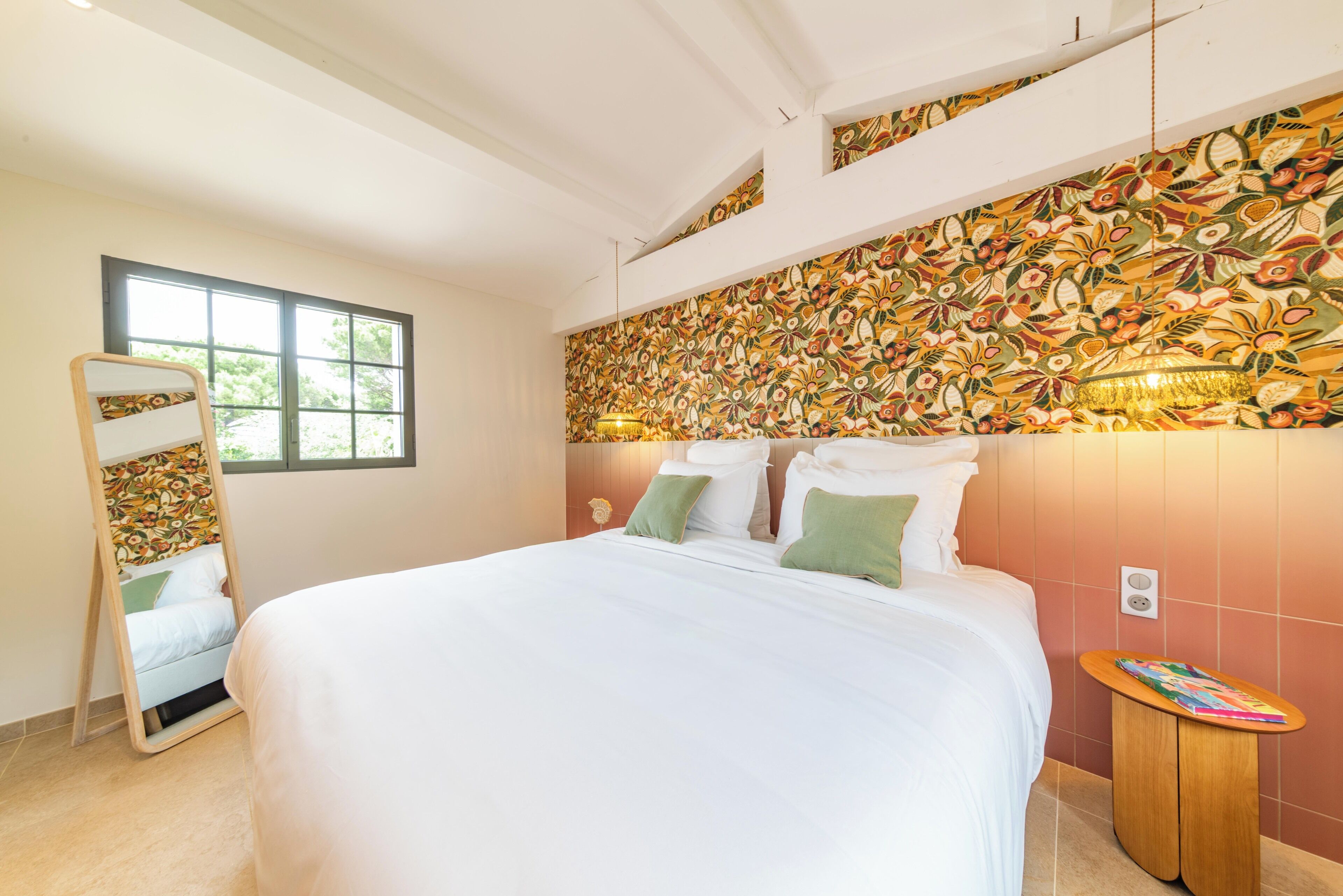 Quarto com uma cama grande, um espelho, uma janela e parede com padrão.