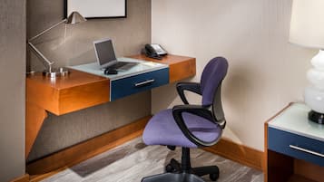 Uma mesa de escritório moderna com um laptop, telefone e abajur.