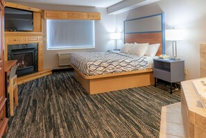 Quarto com cama, televisão, lareira, mesa de cabeceira e banheiro.