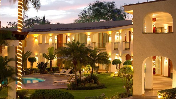 Um hotel com piscina, palmeiras e um pátio bem iluminado.