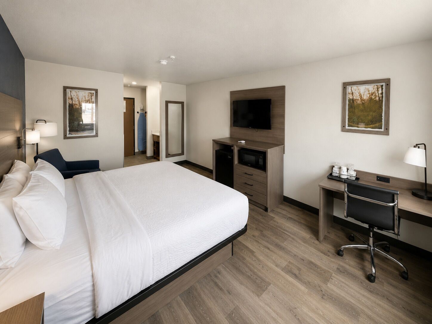 Quarto de hotel com cama, escrivaninha, televisão e obras de arte.