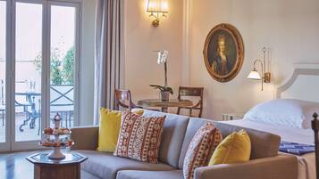 Quarto de hotel com sofá, mesa de jantar com um vaso, cama e um quadro na parede.