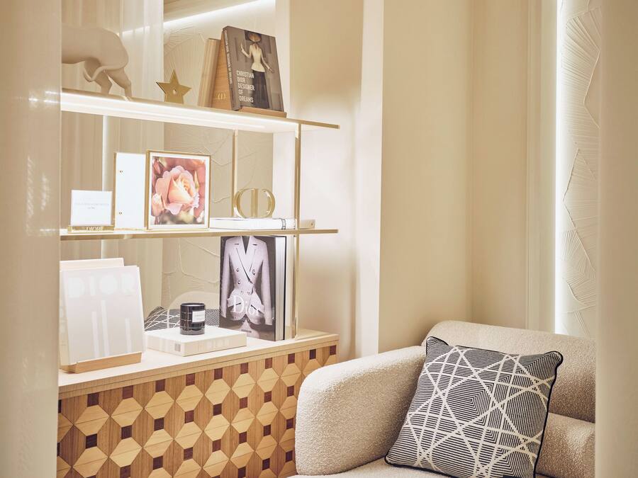 Quarto com uma cama, uma estante com livros e objetos decorativos, e uma parede com padrão geométrico.