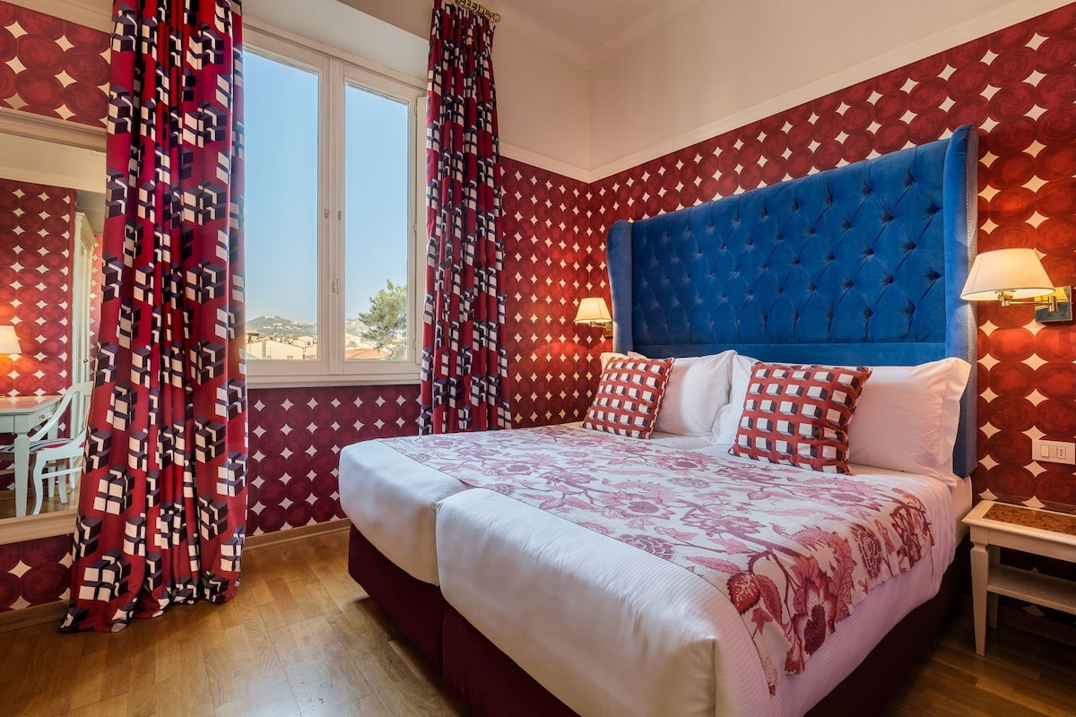 Quarto com cama grande, janela e cortinas estampadas.