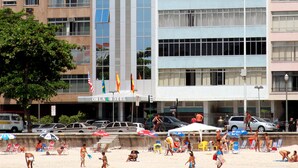Um hotel com vários andares, piscina e cadeiras de praia na areia.