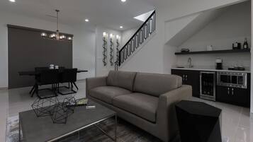 Uma sala de estar moderna com sofá, mesa de centro e área de jantar.