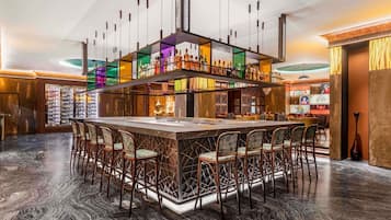 Uma área de bar com ilha central, banquetas e diversas garrafas.