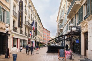 Ruas de pedra com edifícios, uma placa indicando Hotel Florence e uma cafeteria.