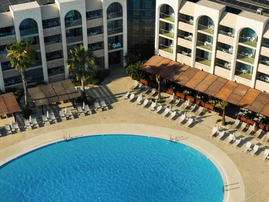 Um hotel com piscina, espreguiçadeiras e zona de estar coberta ao ar livre.