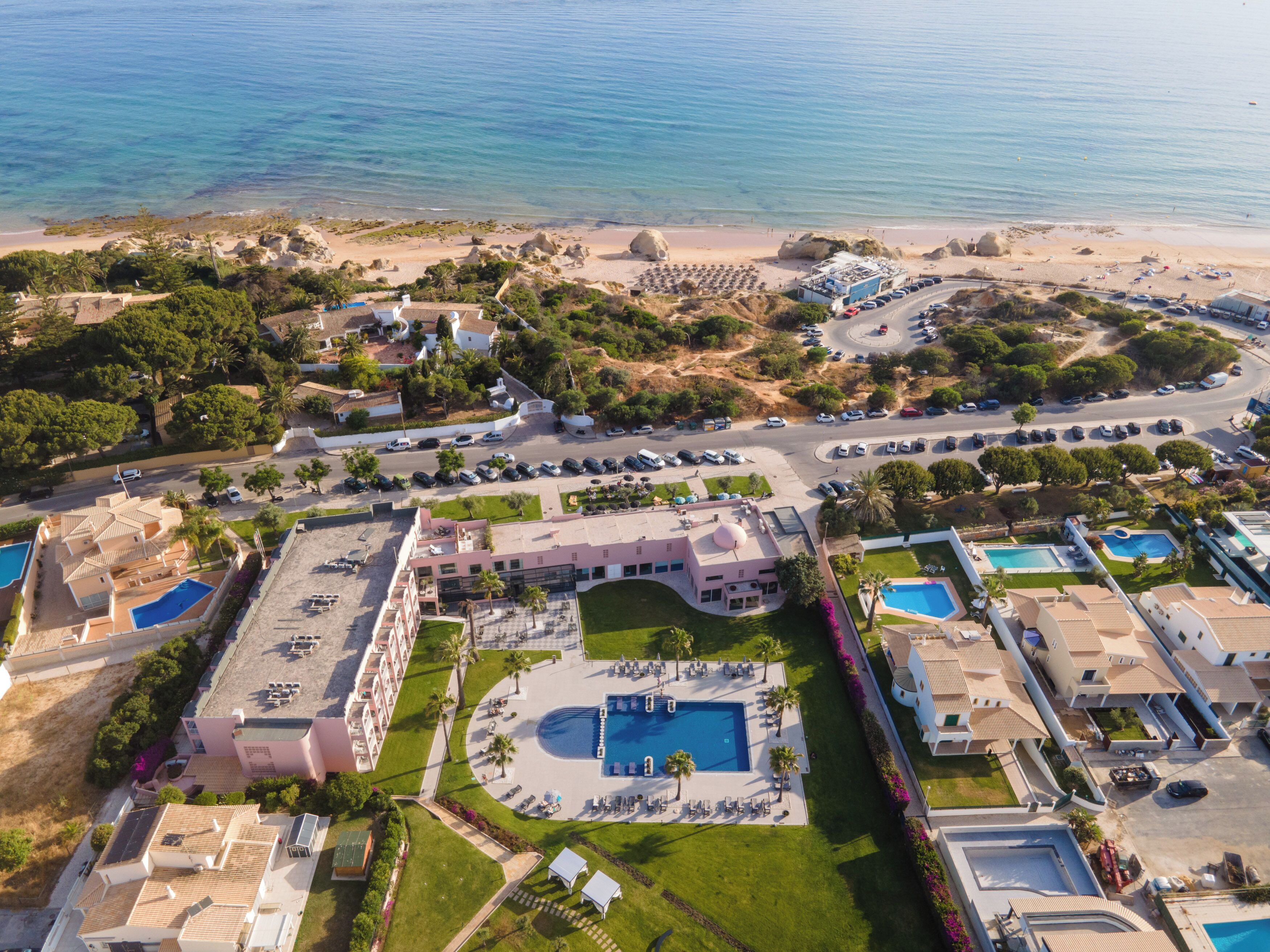 Vista aérea de um resort com várias piscinas, uma praia e um estacionamento.