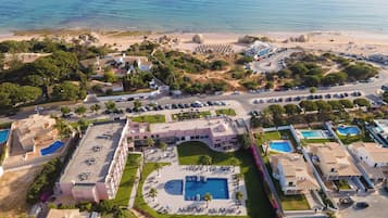Vista aérea de um resort com várias piscinas, uma praia e um estacionamento.