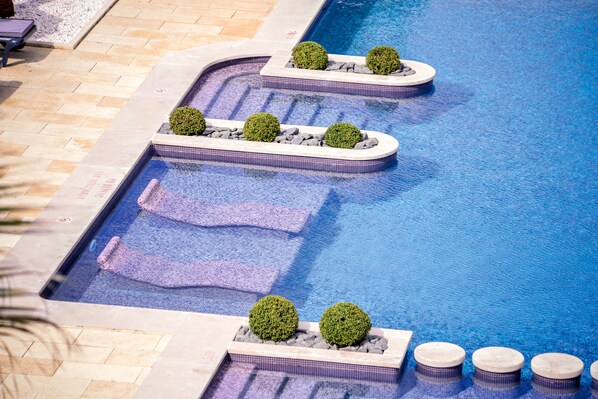 Piscina com vários degraus e vasos com arbustos.