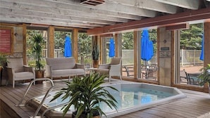 Uma área de piscina coberta com deck de madeira, espreguiçadeiras e guarda-sóis.