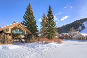 Uma pousada com uma placa que diz "SLOPESIDE CONDOMINIUMS" e uma paisagem coberta de neve.