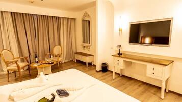 Quarto de hotel com uma cama grande, uma escrivaninha, uma televisão e uma cadeira.
