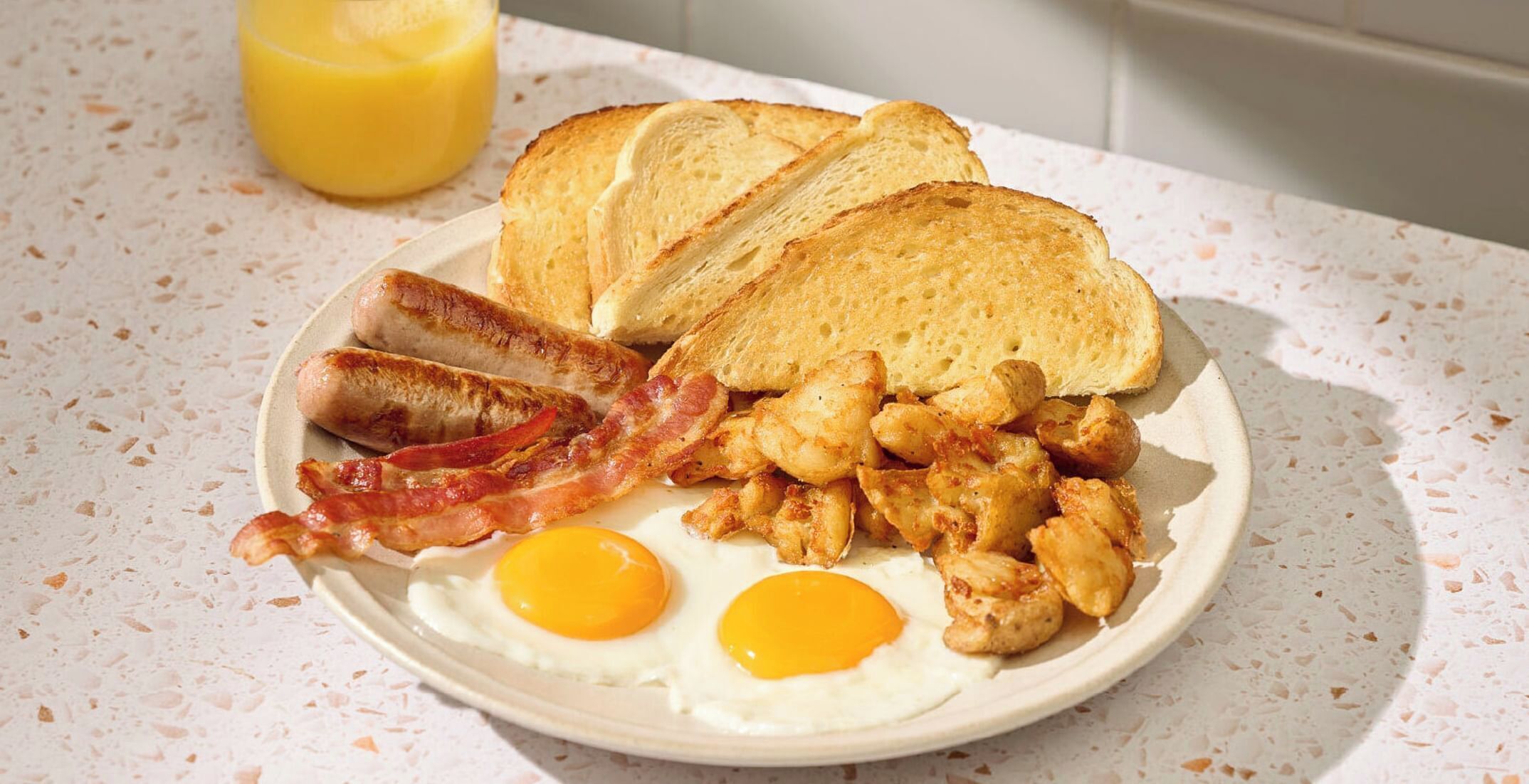 Um prato com ovos, bacon, torradas e linguiça.