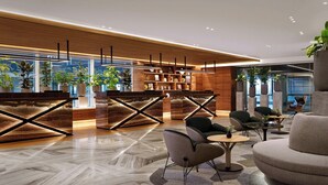 Um lobby moderno com balcão de atendimento em madeira, área de estar e plantas em vasos.