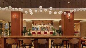 Uma área de bar com um balcão comprido, vários bancos e uma seleção variada de bebidas.
