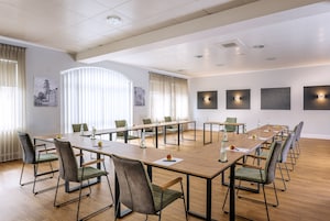 Uma sala de conferências com uma mesa comprida, várias cadeiras e luminárias fixadas na parede.