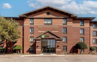 A brick building with a sign reading "extended STAY AMERICA" and a lobby entrance.