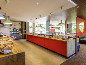 Um café moderno com um balcão extenso, máquinas de café e diversas opções de comida.