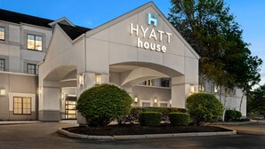 Um hotel moderno com um destaque para a placa 'HYATT house', entrada coberta e paisagismo bem cuidado.
