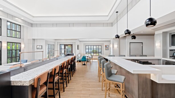 Cozinha espaçosa com bancada comprida, banquetas de bar e luminárias pendentes modernas.