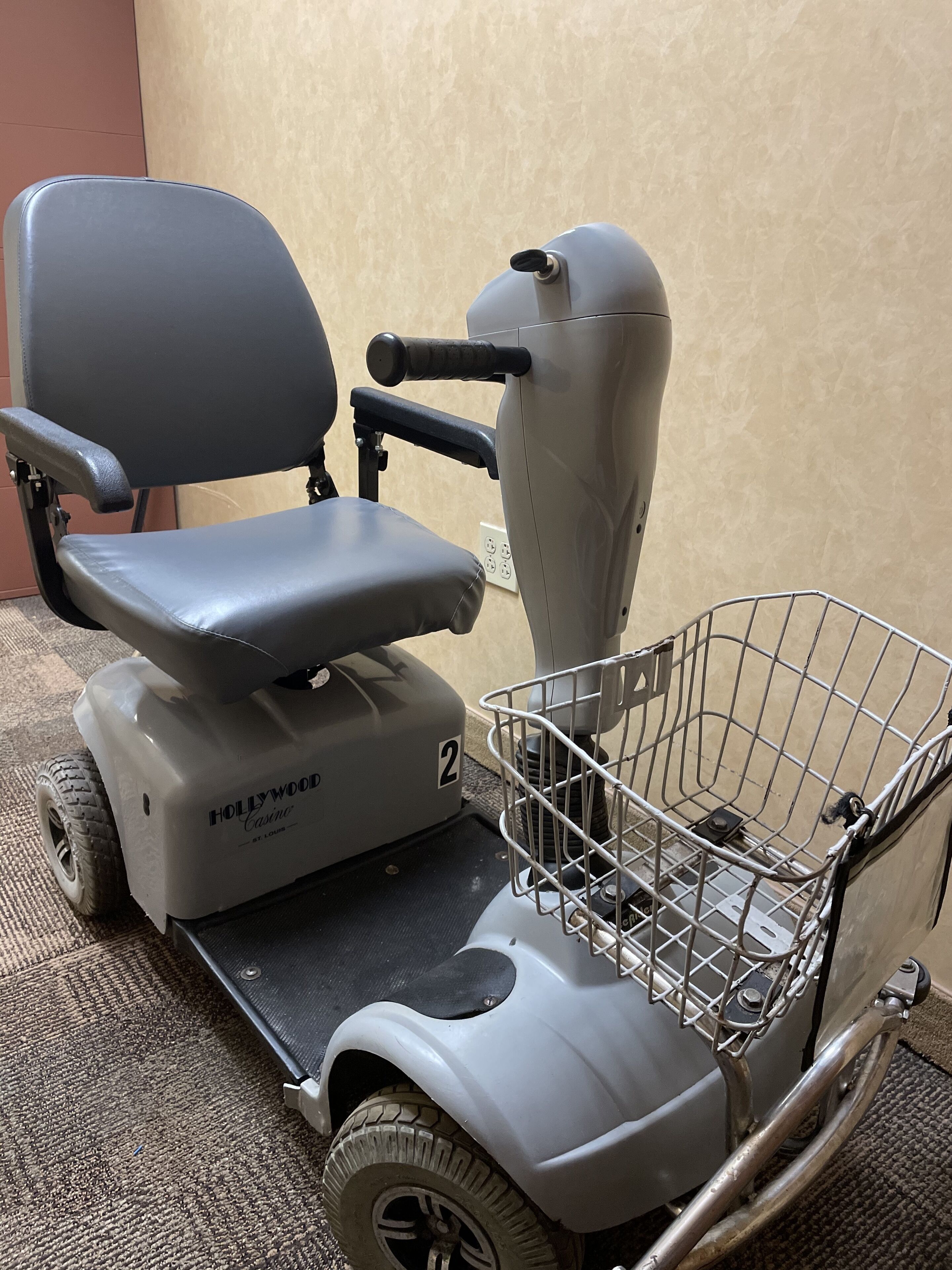 Uma scooter de mobilidade com assento, encosto e cesto de armazenamento.