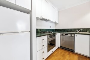 Uma cozinha moderna com armários brancos, fogão de aço inoxidável e lava-louças.