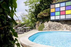 Piscina com espreguiçadeiras e um sinal de correção de cores.