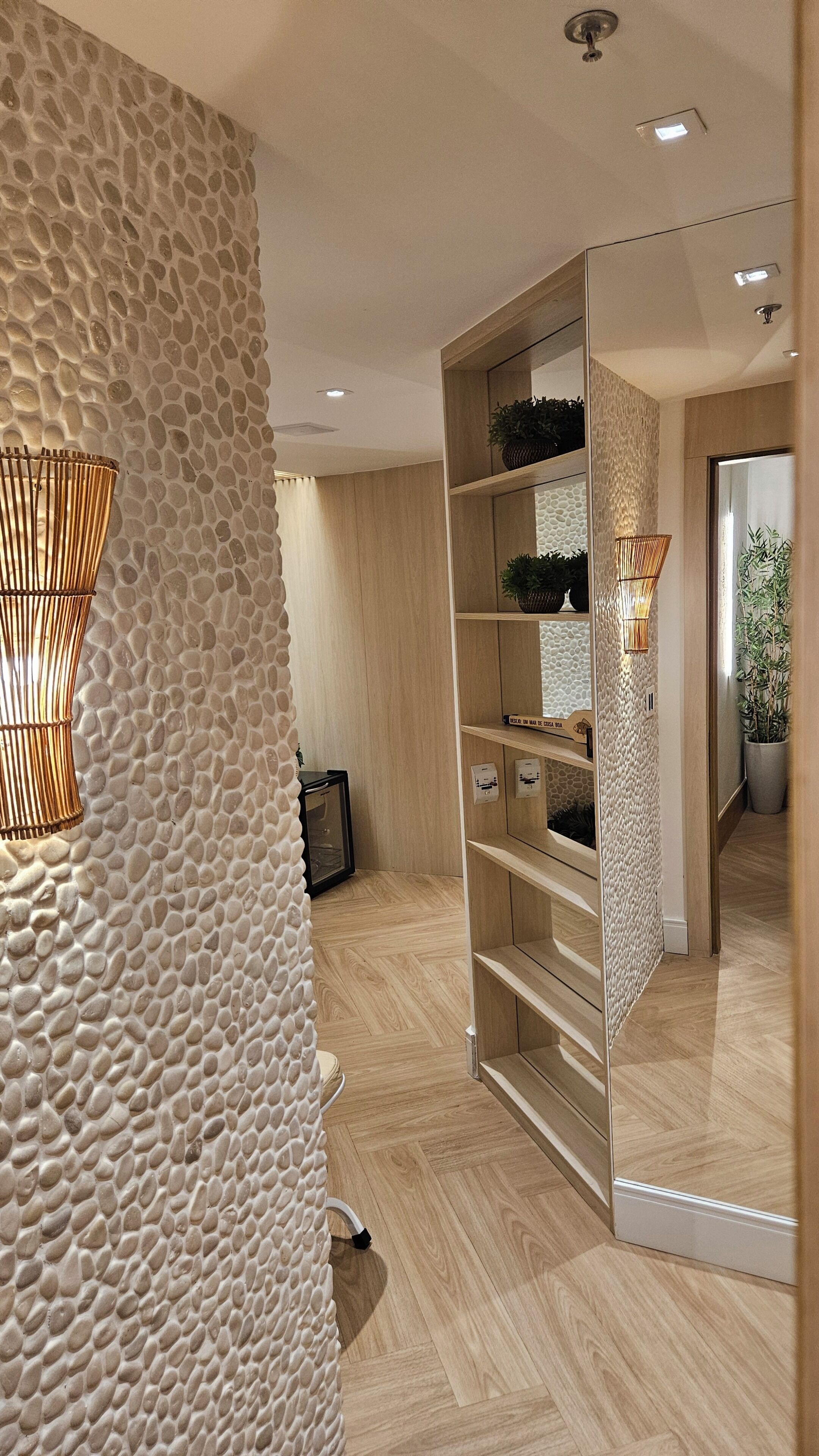 Um interior moderno com parede texturizada, piso de madeira, guarda-roupa espelhado e um vaso com planta.