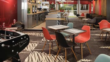 Um restaurante moderno com área de bar, diversas opções de assento incluindo mesas e cadeiras, e uma cozinha visível ao fundo.