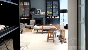Uma sala de estar moderna com lareira, estantes de livros, um sofá e uma mesa de jantar.