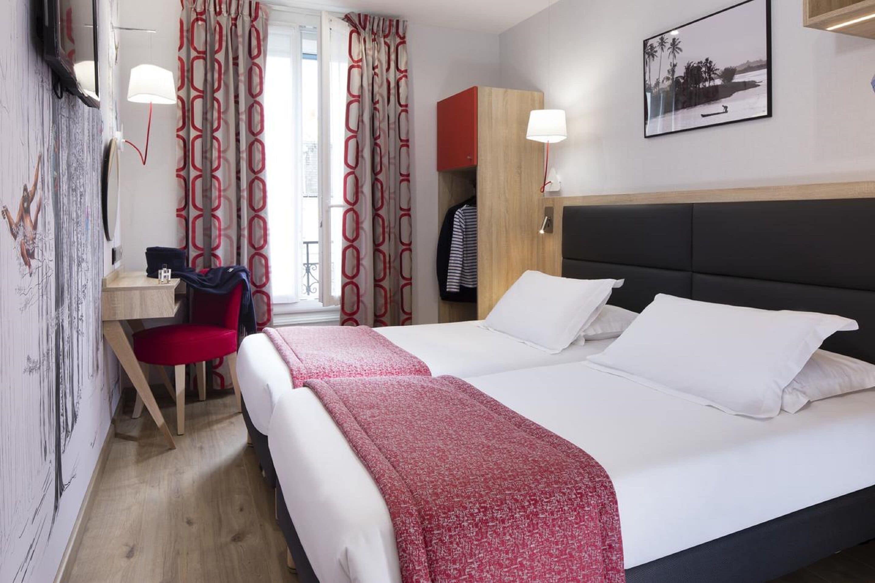 Quarto de hotel com duas camas, uma escrivaninha, uma cadeira e um guarda-roupa.