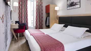Quarto de hotel com duas camas, uma escrivaninha, uma cadeira e um guarda-roupa.