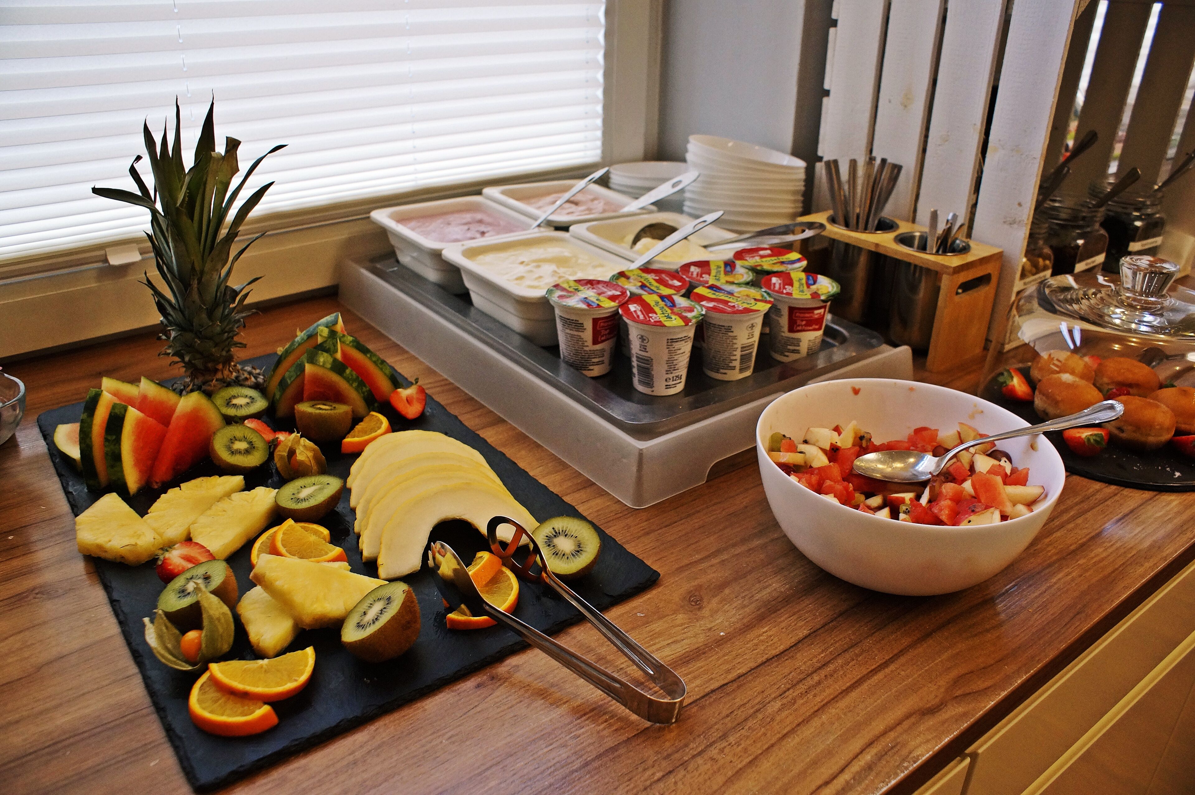Buffet com diversas frutas e copos de iogurte.