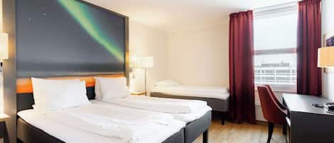 Quarto de hotel com uma cama grande, uma cama menor, uma mesa e uma cadeira.
