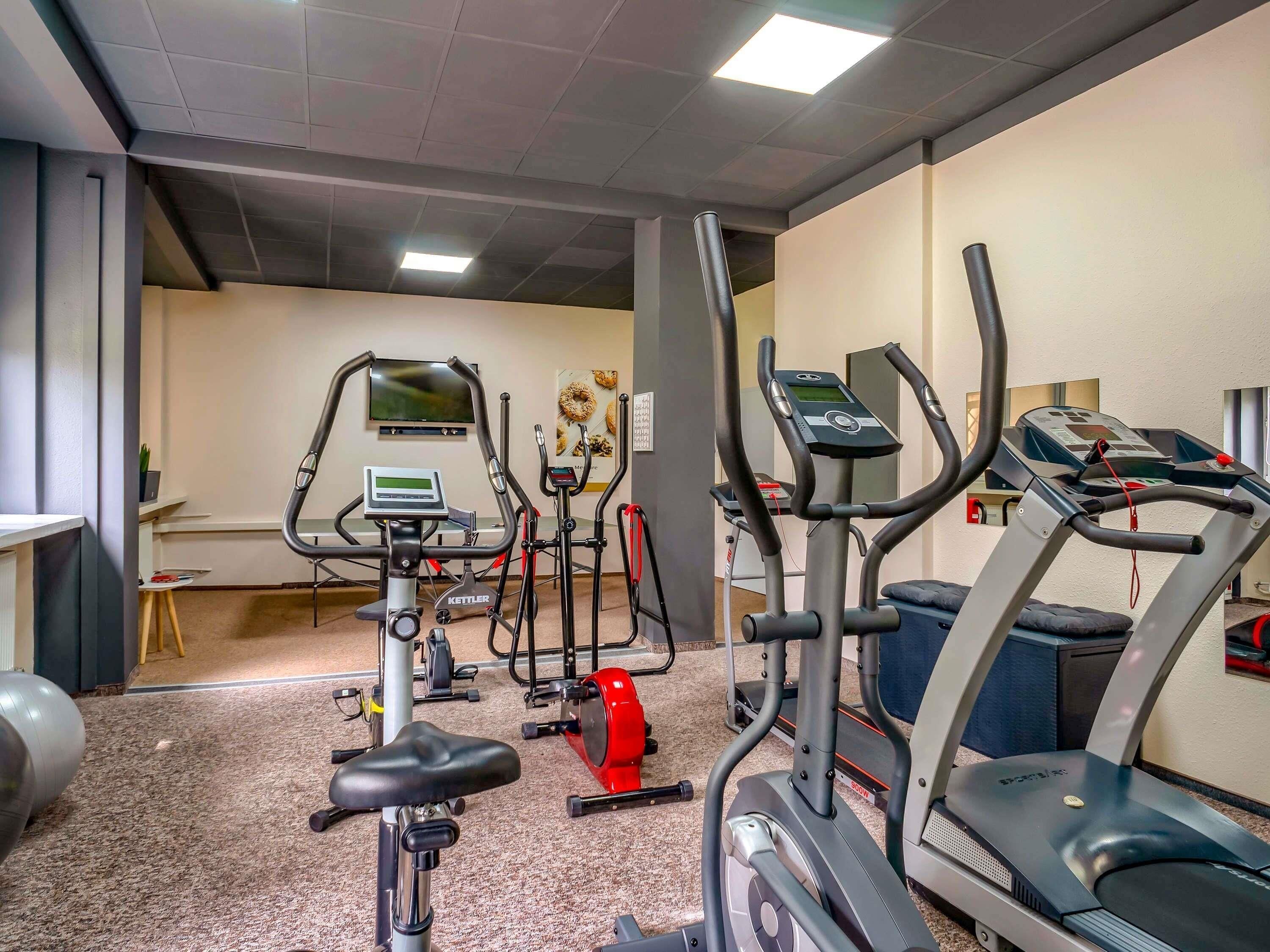 Uma academia com diversos equipamentos de exercício, incluindo esteiras, bicicletas ergométricas e elípticos.