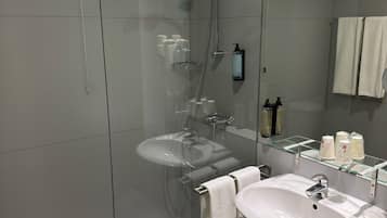 Uma casa de banho moderna com chuveiro envidraçado, lavatório branco e espelho sobre o lavatório.
