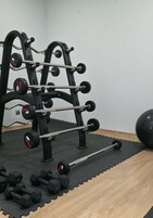 Uma academia com suporte para agachamento, barra e halteres.