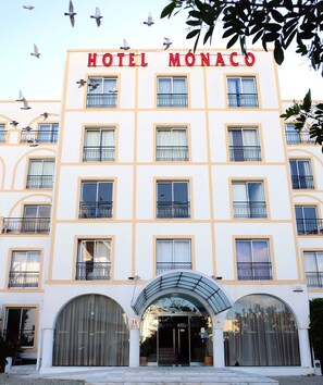 Um edifício de hotel com várias varandas e uma placa que diz 'HOTEL MONACO'.