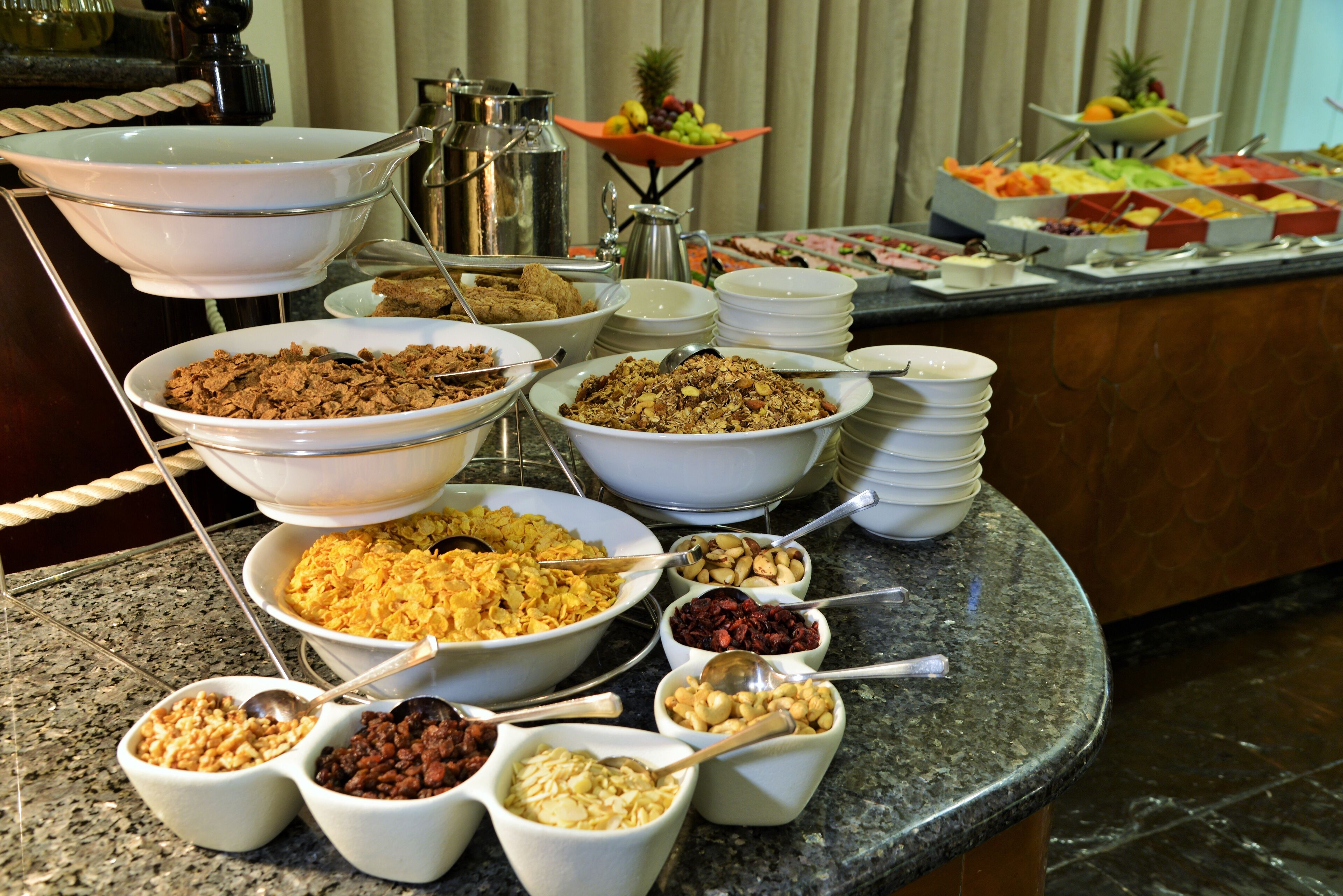 Buffet com diversos alimentos e utensílios de servir.