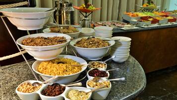 Buffet com diversos alimentos e utensílios de servir.