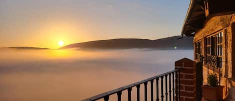 Nascer do sol sobre uma paisagem enevoada com uma varanda com vista.