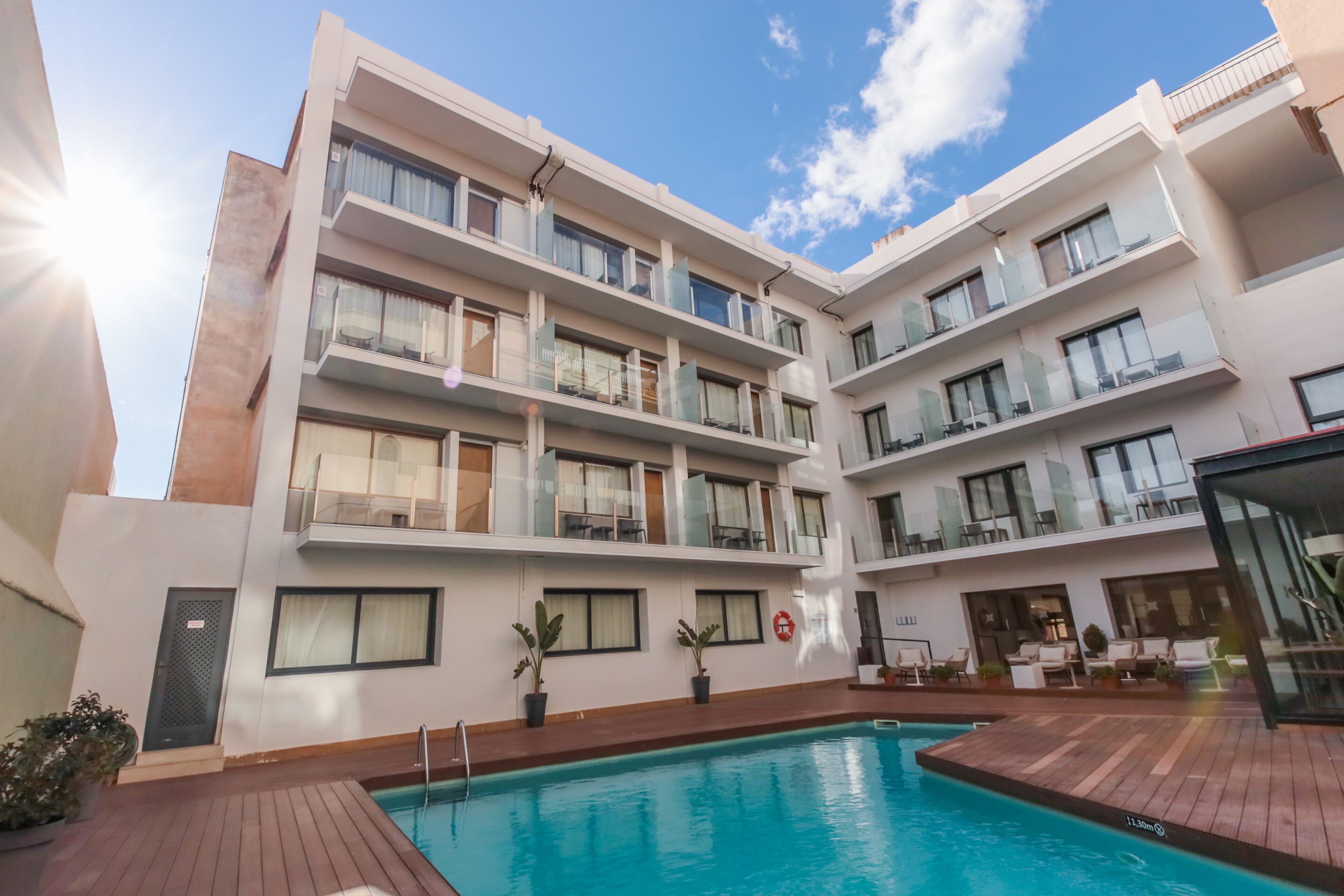 Um hotel moderno de vários andares, com piscina, varandas e áreas de estar ao ar livre.