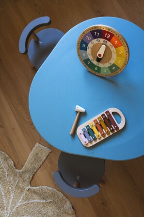 Uma mesa azul com piso de madeira, um martelo de brinquedo colorido e um brinquedo de madeira com mostrador colorido.