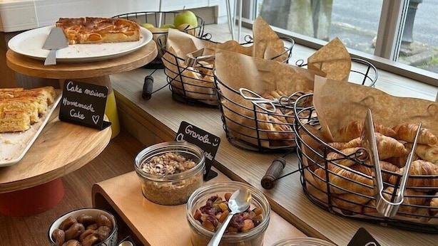 Buffet de café da manhã com diversos alimentos e etiquetas.