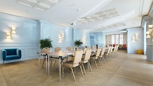 Uma sala de jantar ampla com uma mesa comprida e cadeiras, paredes azul-claras e luminárias modernas.